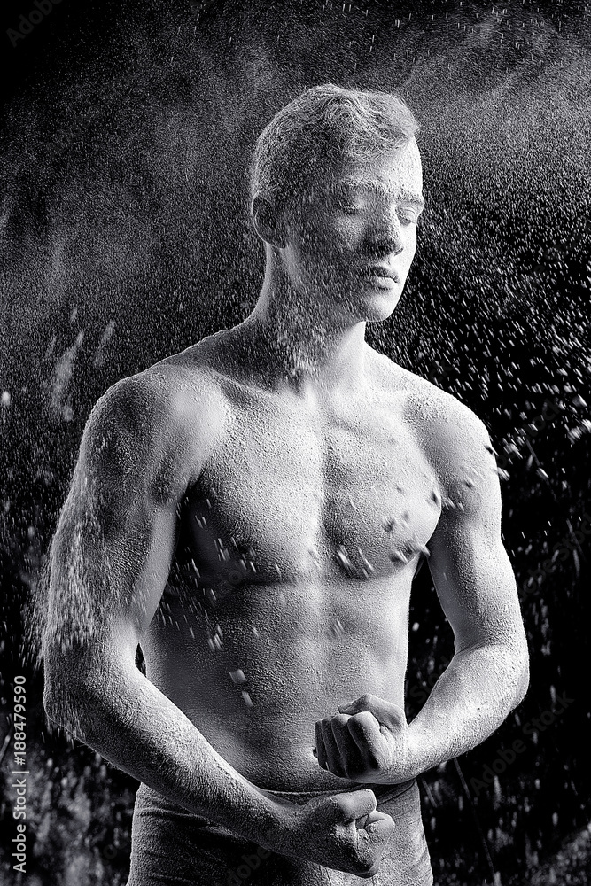 Athletic man covered in flour with strained muscles with thrown flour ...