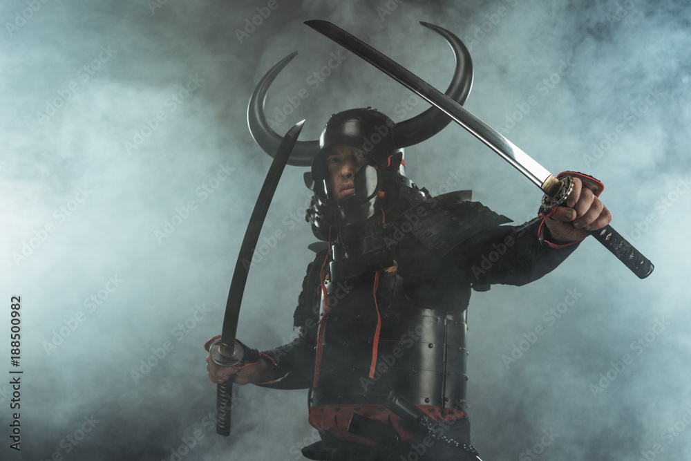 Samurai in traditional armor with dual katana swords in defense ...