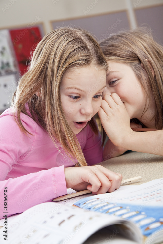 Young female students gossiping in class Stock Photo | Adobe Stock