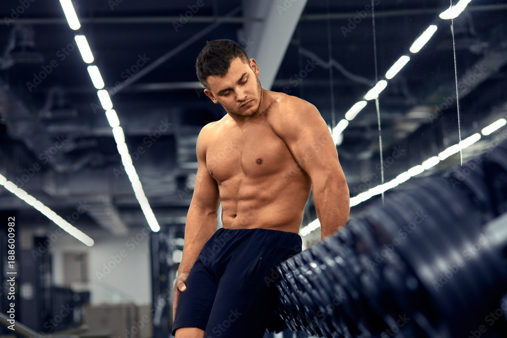 Muscular bodybuilder in gym near dumbbell rack.Strong athletic man ...