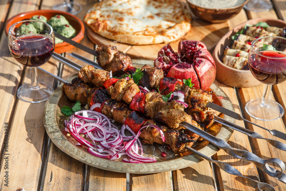 Meat shish kebab on a plate with onions, pomegranate seeds, hot pepper ...