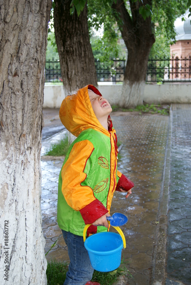 Little girl hides under a tree from the rain Stock Photo | Adobe Stock