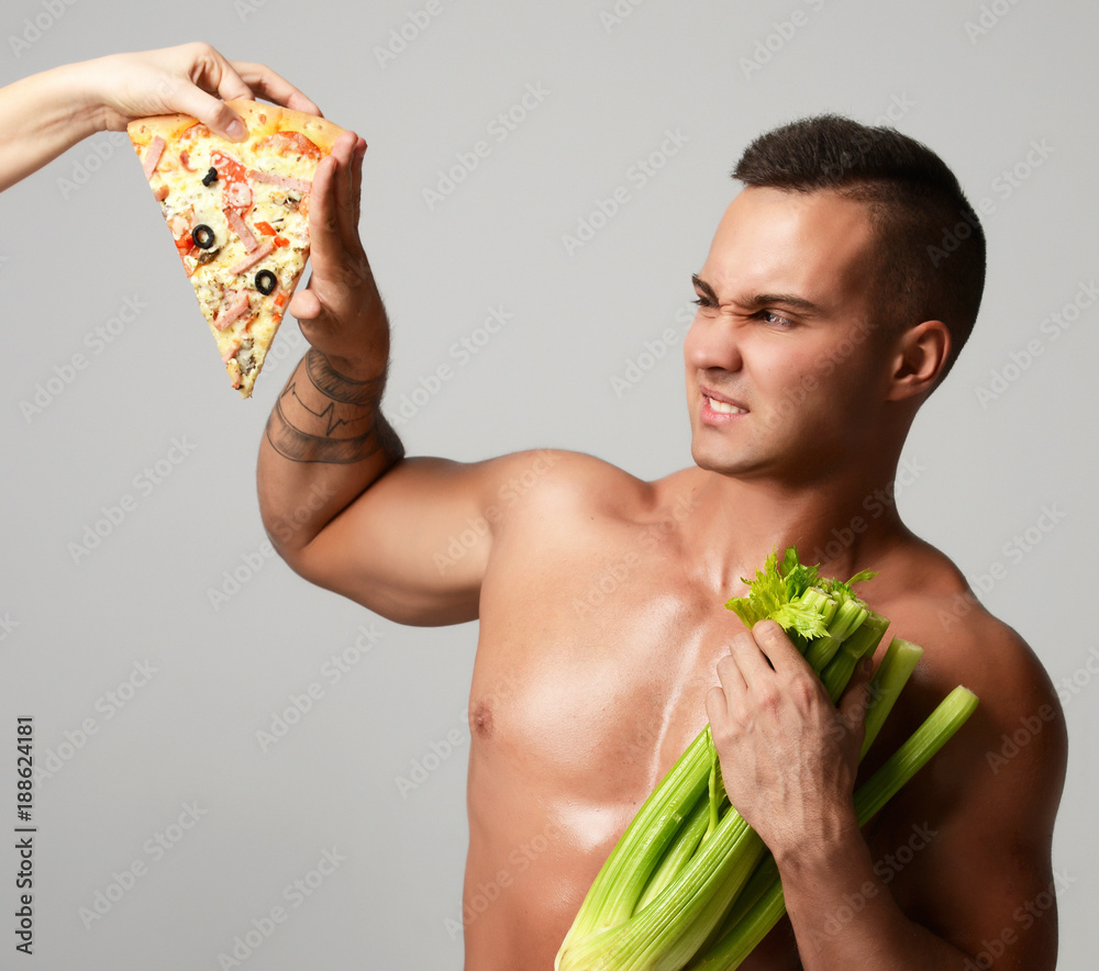 Strong muscular athlete men with fresh celery and unhealthy pizza fast ...