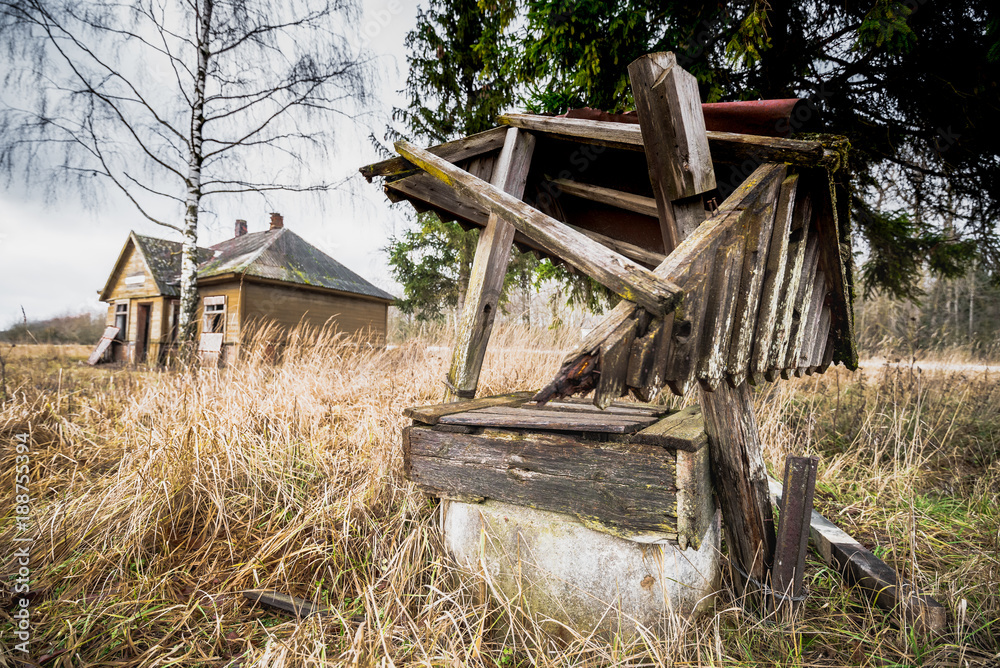 Old wooden abandoned well and house Stock Photo | Adobe Stock