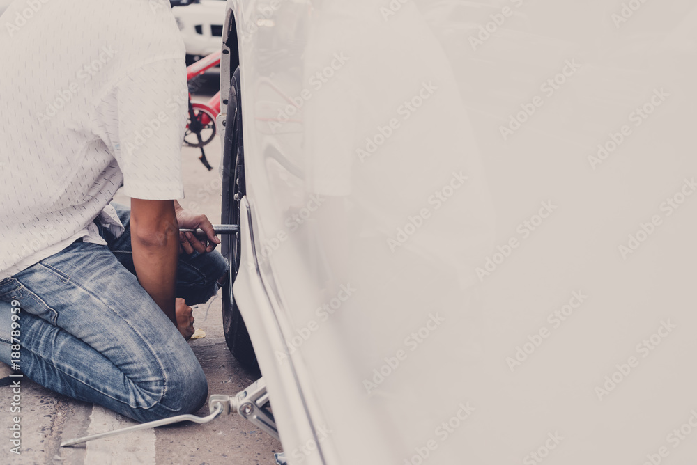 Man changing flat tire on the road .Replacing the tires on the car ...