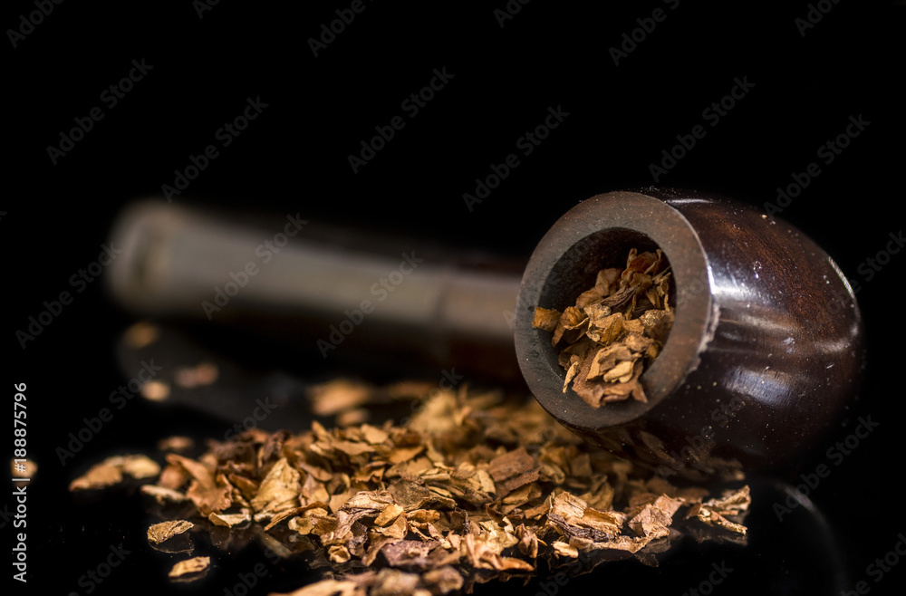 Tobacco Smoking pipe and tobacco spilled on a reflective glass surface ...
