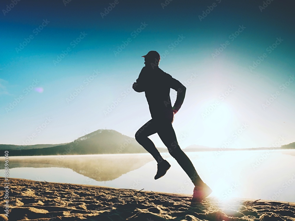 Foto de Tall fit man running along the sea shore in morning. Healthy ...