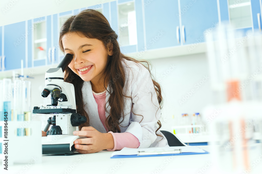 Little child with learning class in school laboratory using microscope ...