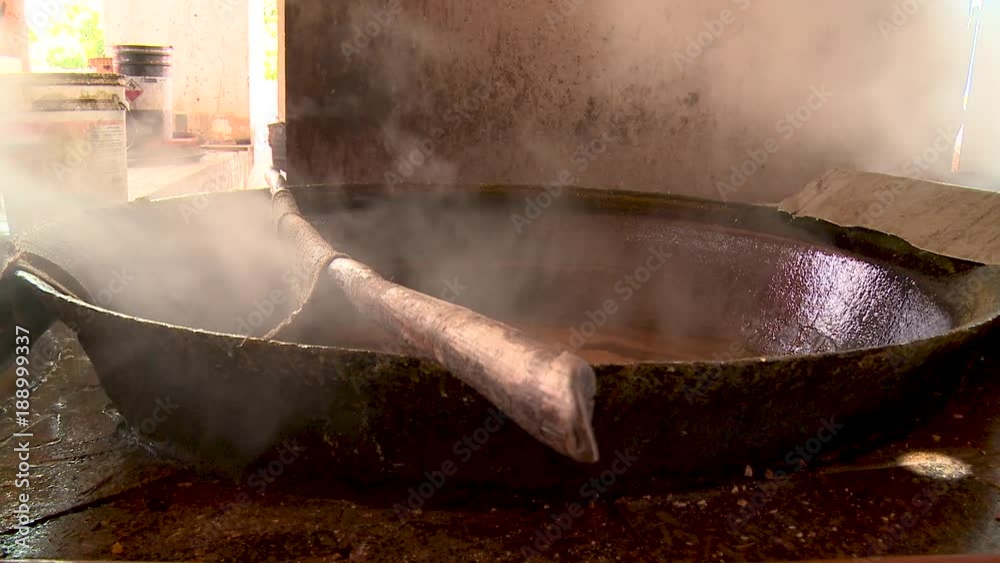 Sugar cane juice is scooped into a heated vat through a filtering cloth ...