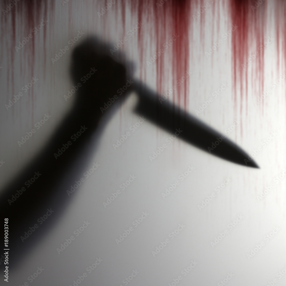 Shadow of hand holding knife to pierce the victim behind a transparent ...