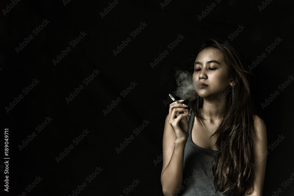Woman Smoking a Cigarette on Black Background. Portrait of a beautiful ...