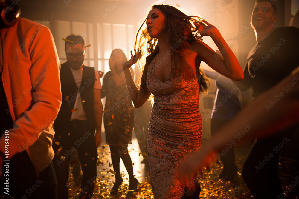 Crowd of trendy young people dancing in nightclub with golden confetti ...