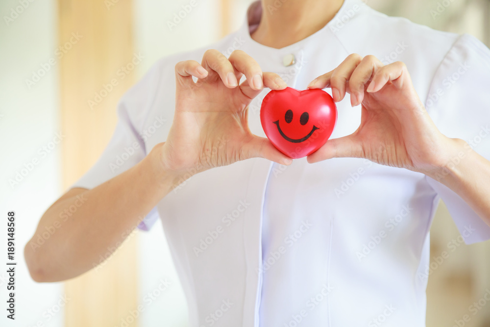 Red smiling heart held by female nurse's both hands, representing ...