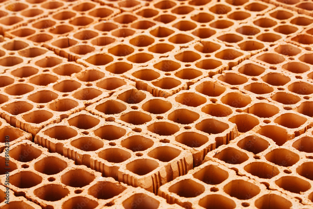 Pile of red hollow bricks with large holes forming a repetition ...