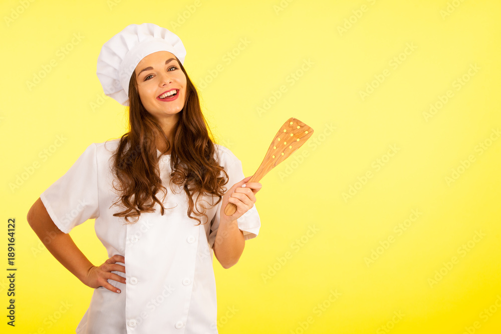 Beautiful chef - cute brunette woman in cook uniform over yellow ...
