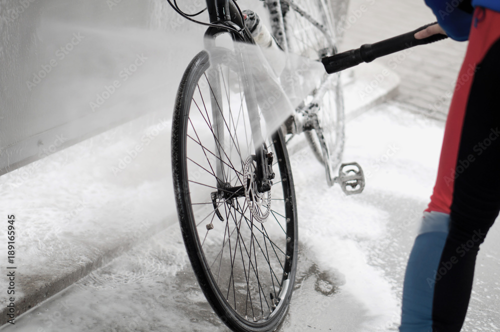 Man washing the bike with a strong jet of water. Washing the bike after ...