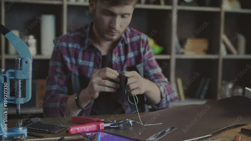 Leather manufacturer sewing needle in home workshop. Craftsman making ...