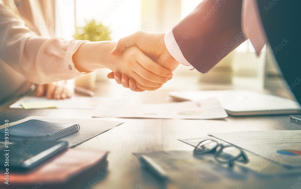 Businessman and businesswoman shaking hands above desk Stock Photo ...