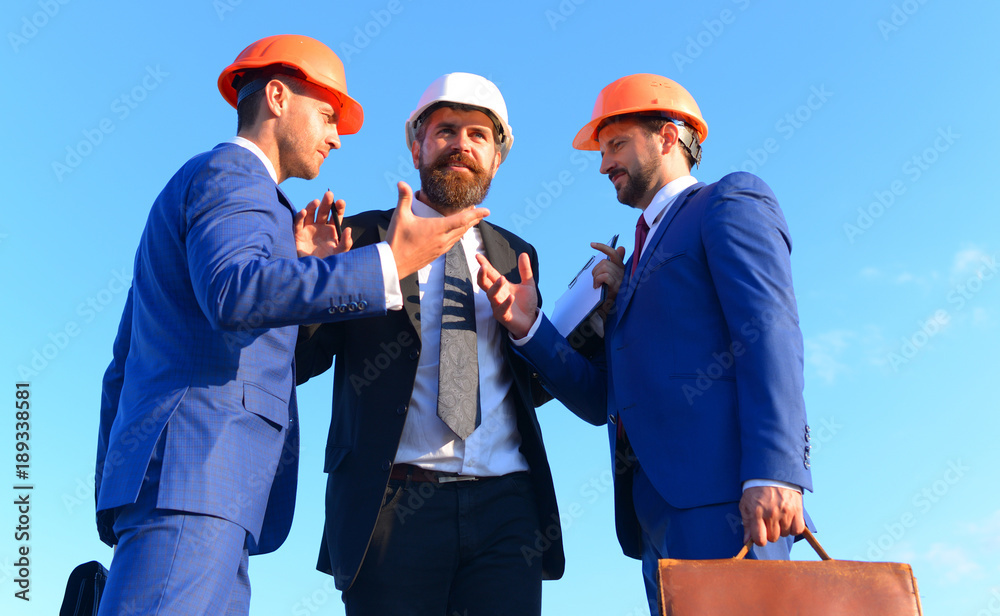 Builders discussing plan and argue, blue sky background. Stock Photo ...
