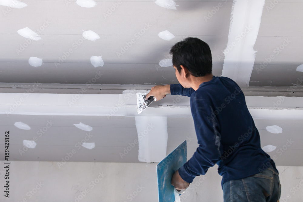 Construction man worker plaster gypsum ceiling for interior build ...
