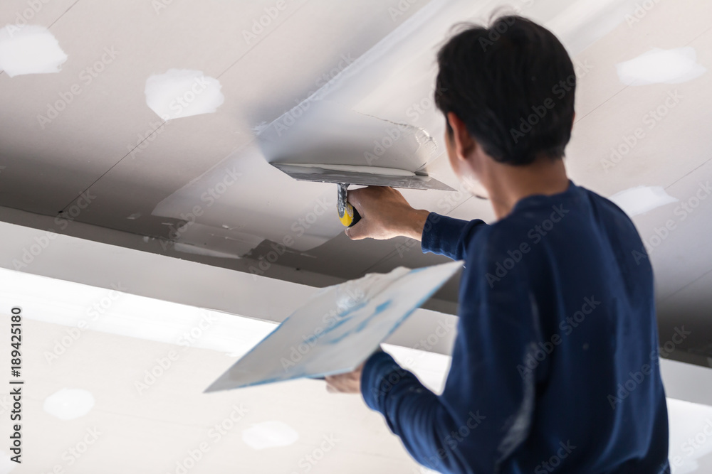 Construction man worker plaster gypsum ceiling for interior build ...