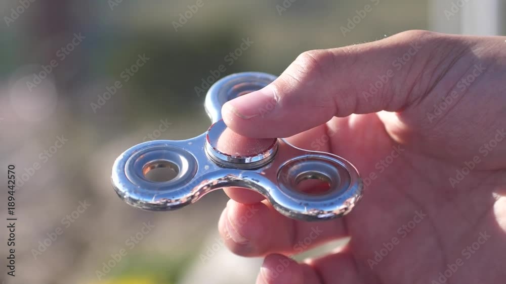 The man's hand is held by a spinning spinner in his hand. slow motion ...