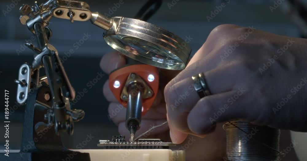 Hobbyists' hands soldering an electrical connection on circuit board ...