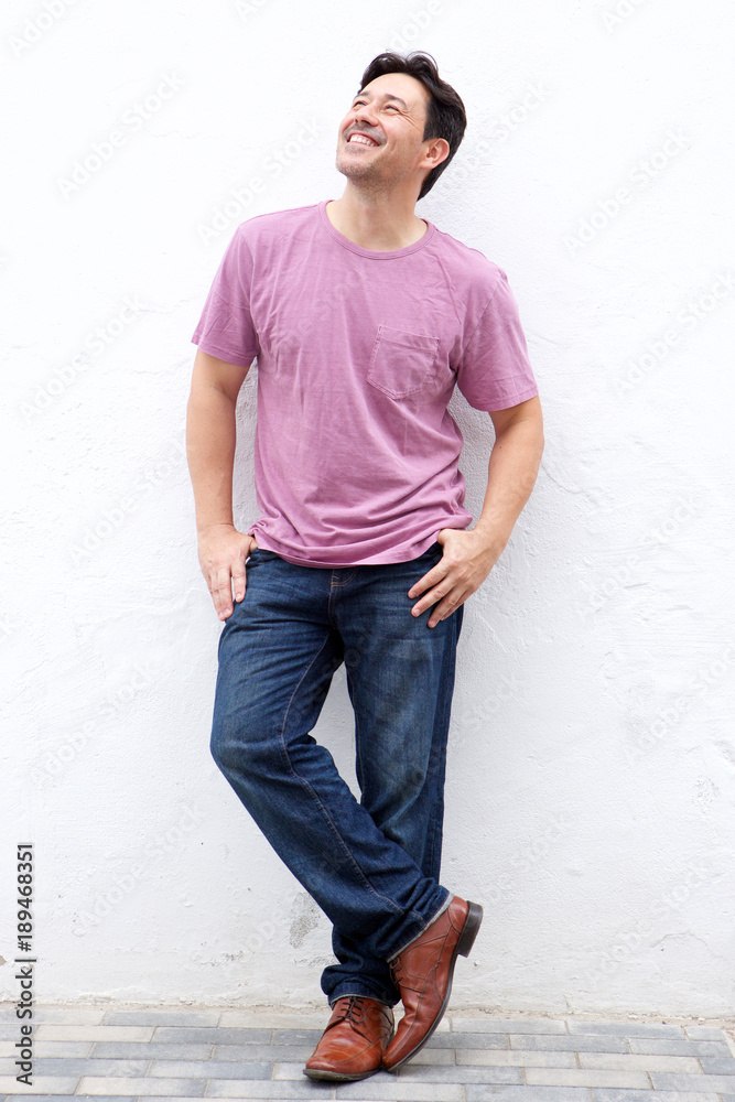 cool middle aged man standing against white wall and looking away ...