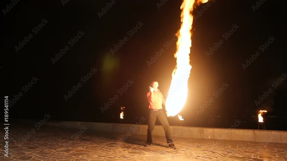 Artist man rotates the fireball.Man twist fiery circles on a fire show ...