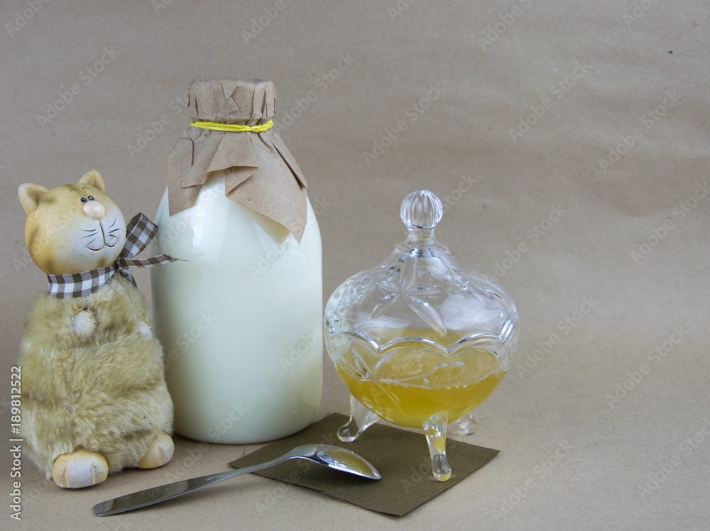 composition of a figurine of a ceramic cat, milk in a bottle and honey ...