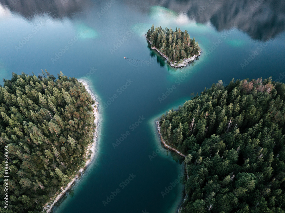 Small boat on lake Eibsee in south Germany with large forest and hidden ...