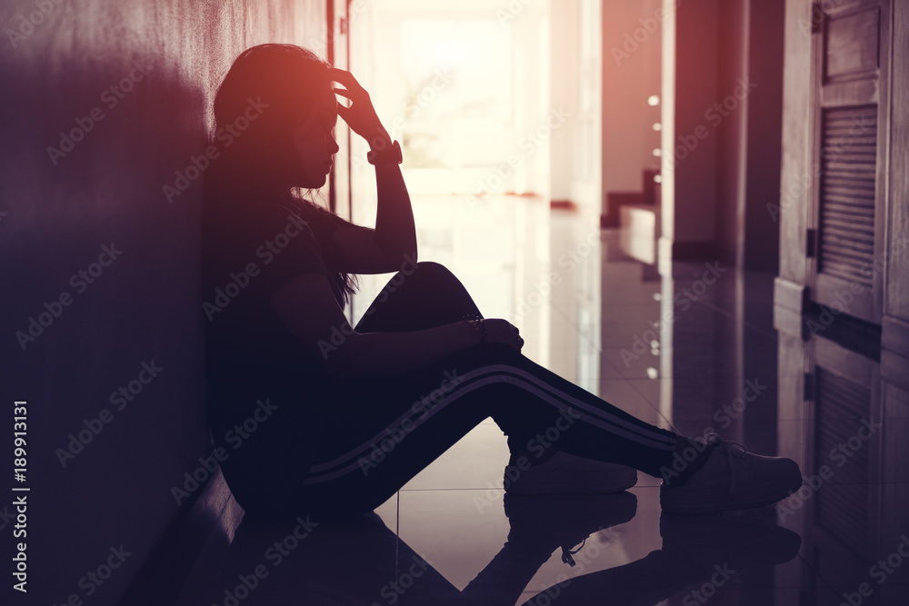 Silhouette of sad and depressed women sitting at walkway of condominium ...