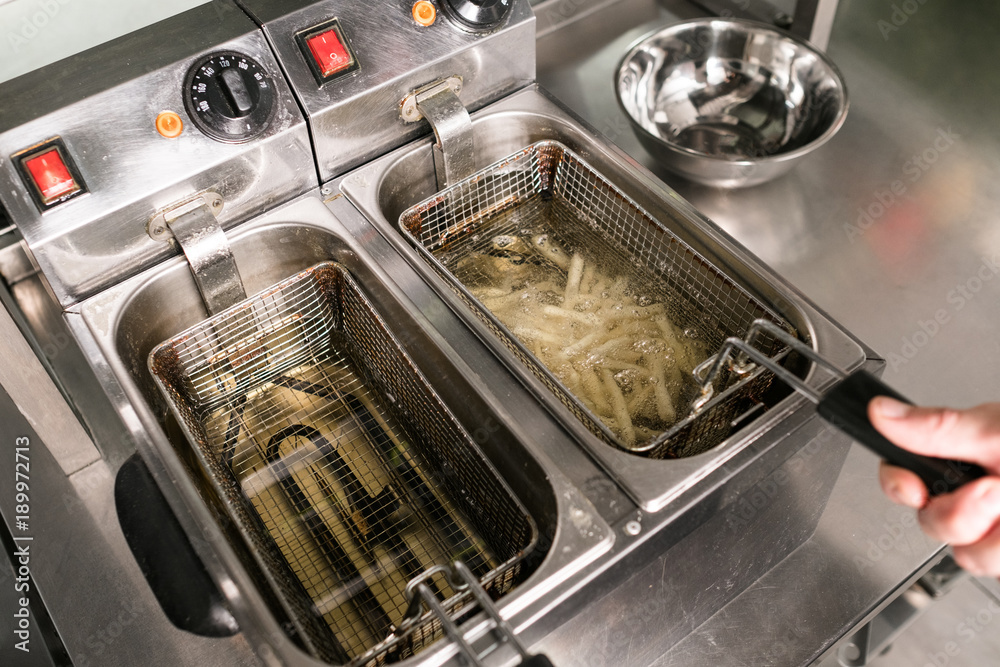 French fries - best junk food ever. Cook preparing fast food in the ...