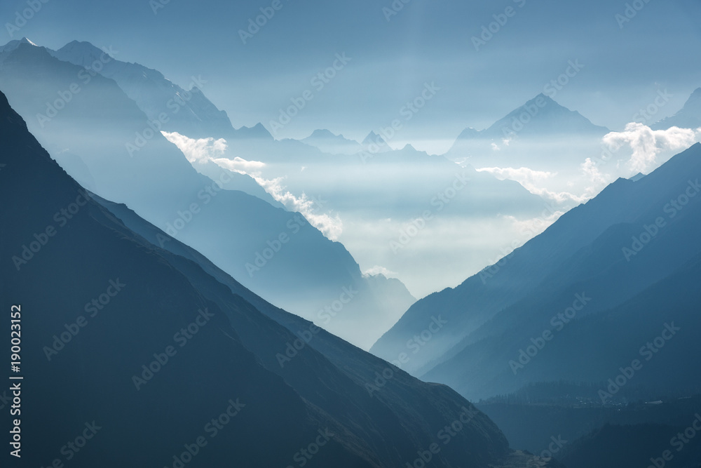 Majestic view of silhouettes of mountains and low clouds at sunset in ...