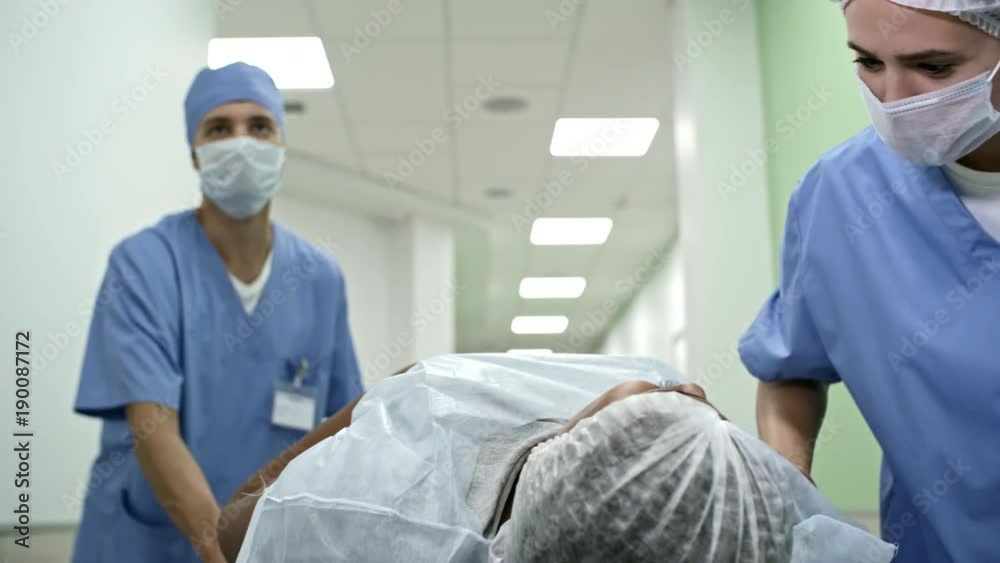 Dolly of female nurse in scrubs pushing pole with IV drip and walking ...
