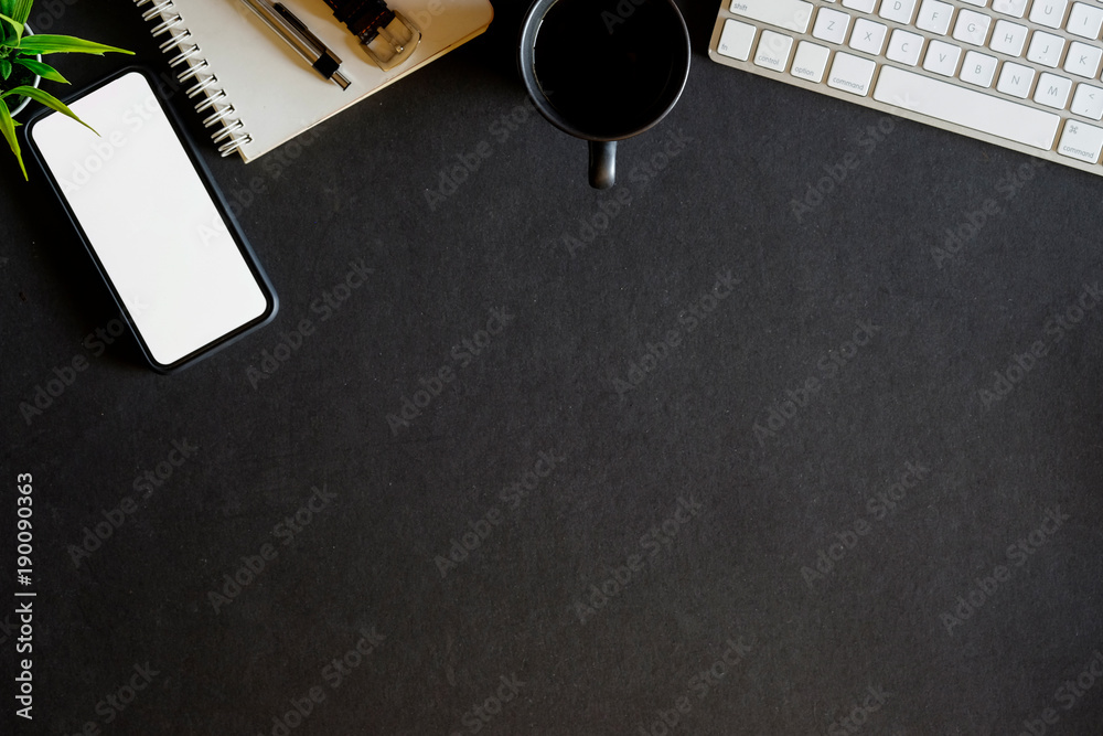 Dark office desk table with desktop computer, smartphone, coffee and ...