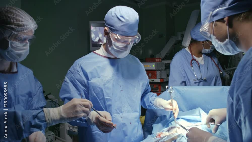 PAN of skillful surgeons in scrubs and masks operating on unconscious ...