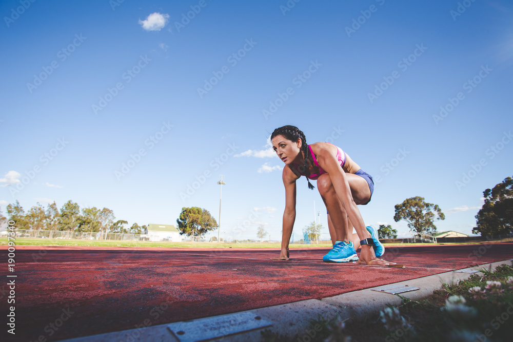 Female fitness model and track athlete sprinting on an athletics track ...