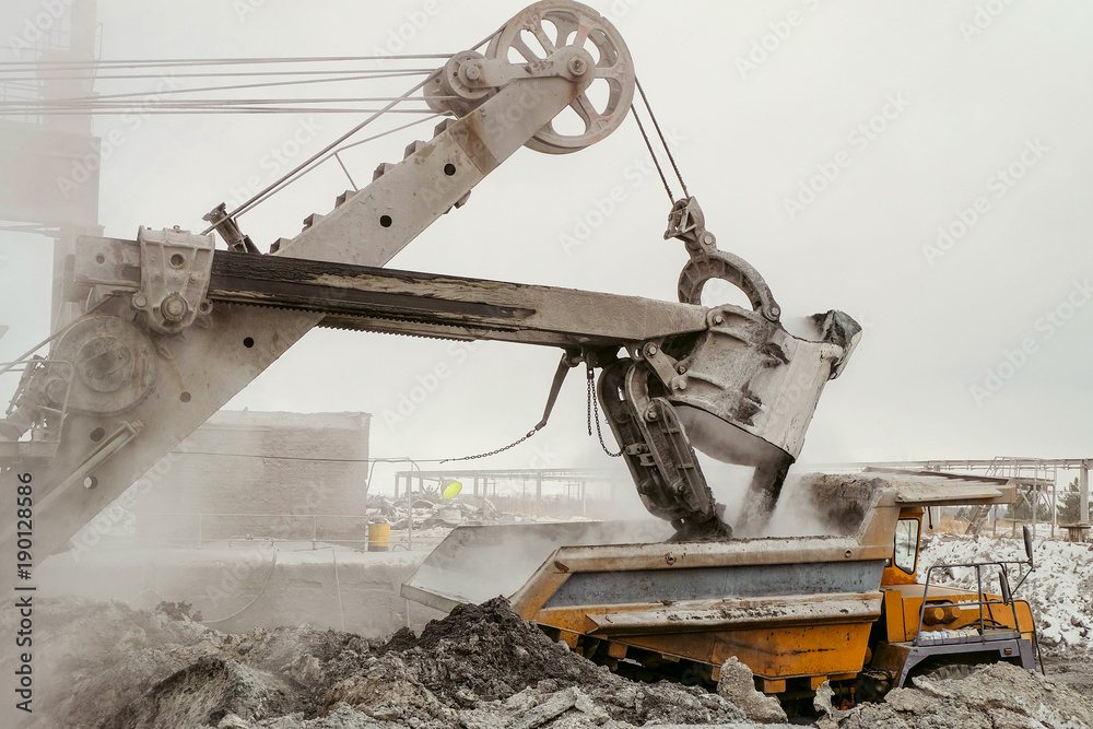Heavy excavator loads slag into a big mining dump truck. Work in heavy ...