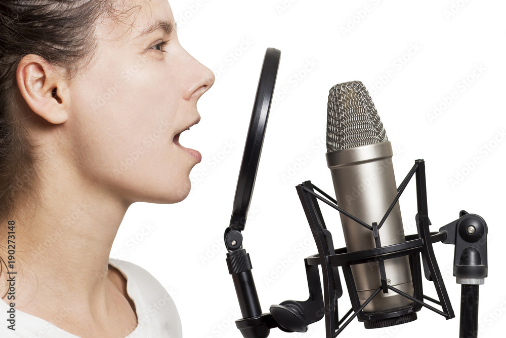 Brunette girl records voice to studio microphone. Young woman sings in ...