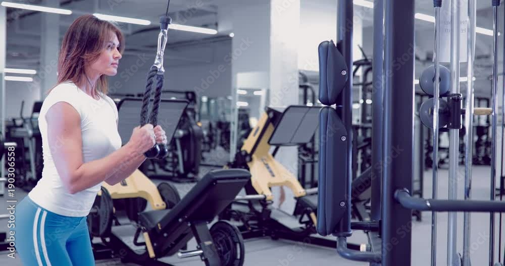 Adult woman doing Exercises for Tricep in fitness gym. Beautiful Woman ...