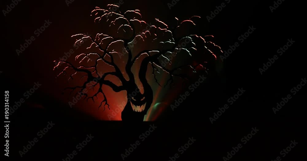 Silhouette of scary Halloween tree with horror face on dark foggy toned ...