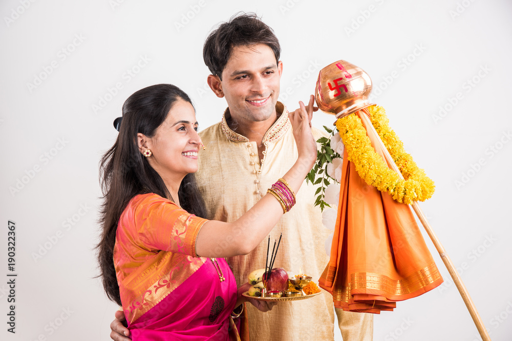 portrait of happy indian couple standing with puja or pooja thali doing ...