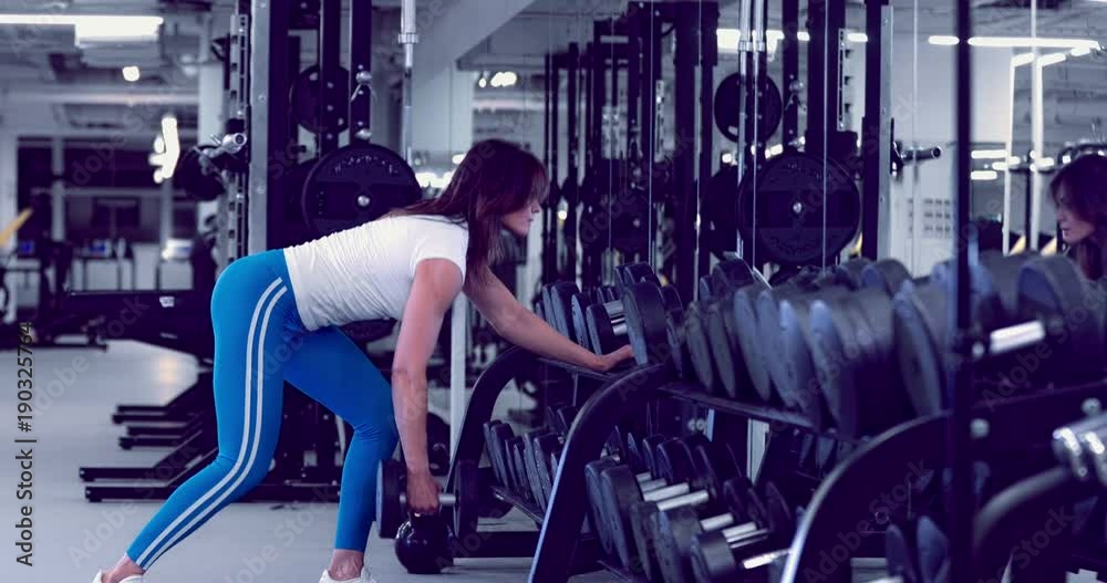 Fitness woman do exercises on the muscles of the back with dumbbell in ...