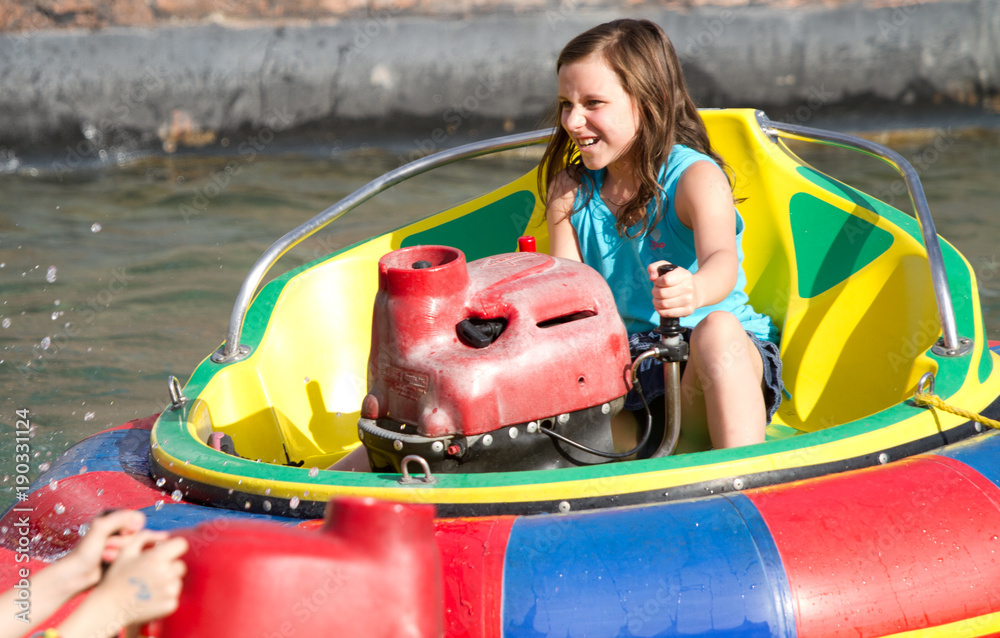 Eight years old girl is driving bumping boat in entertainment park in ...
