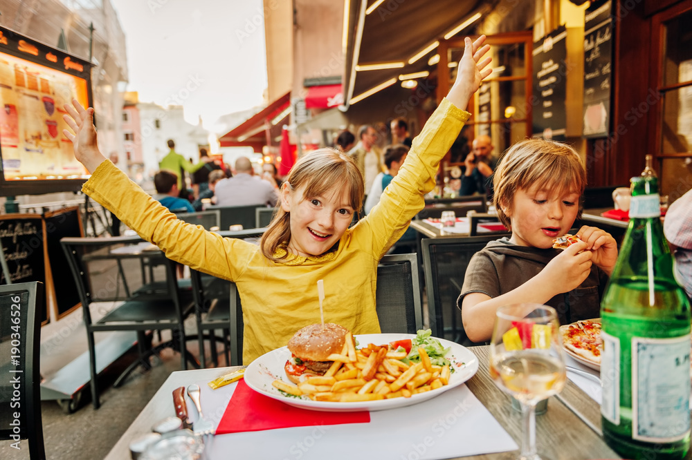 Happy kids eating hamburger with french fries and pizza in outdoor ...