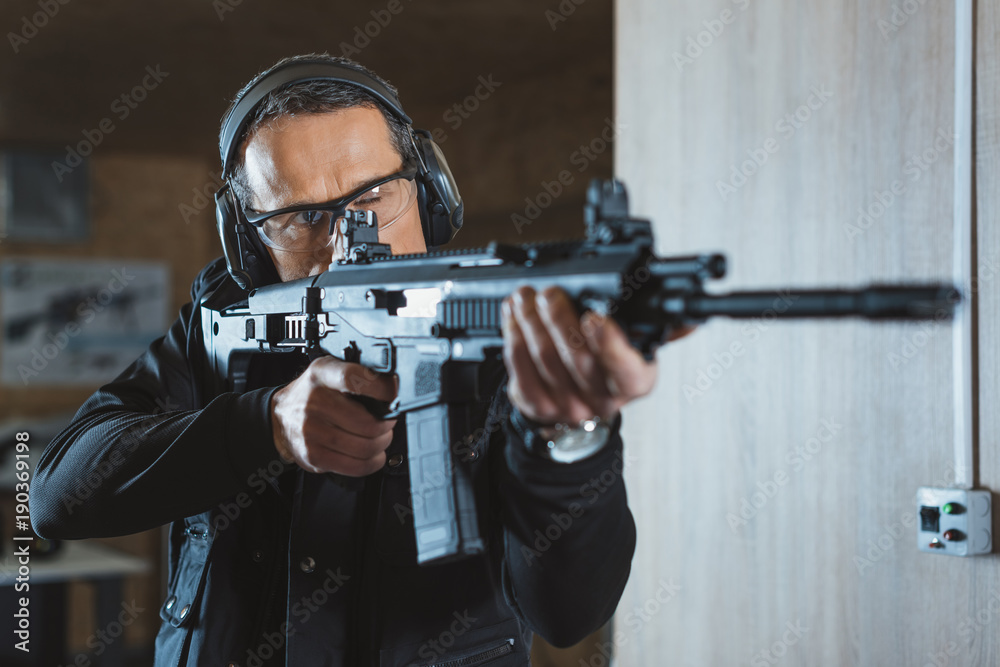 handsome man aiming rifle in shooting range Stock Photo | Adobe Stock