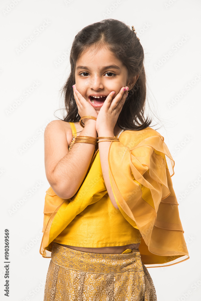 happy Indian girl child in ethnic wear or traditional wear, holding ...