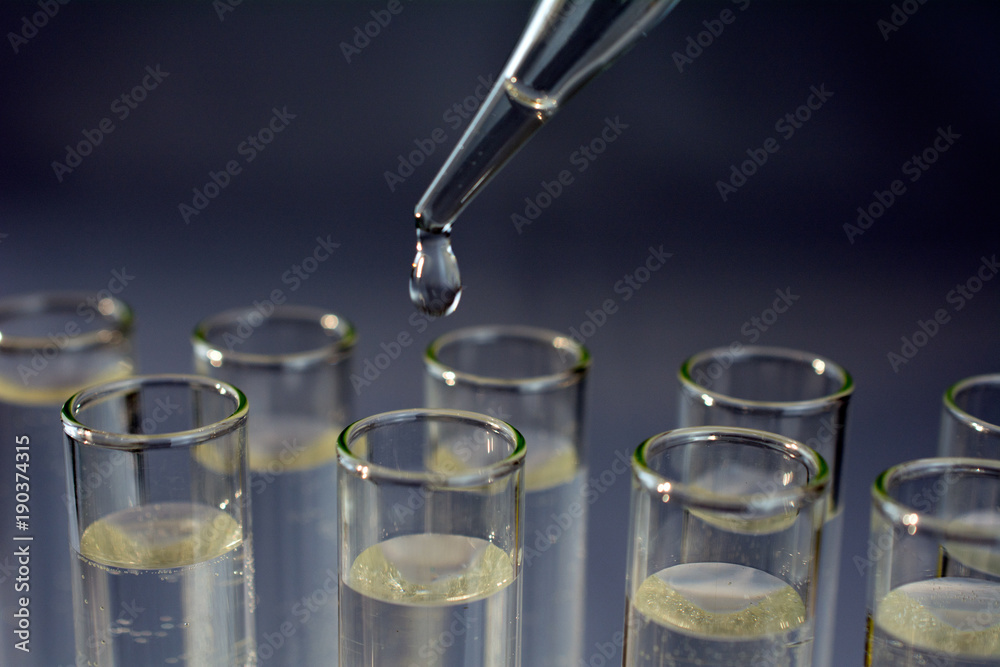Glass test tubes with laboratory clear liquids, drops from a pipette ...