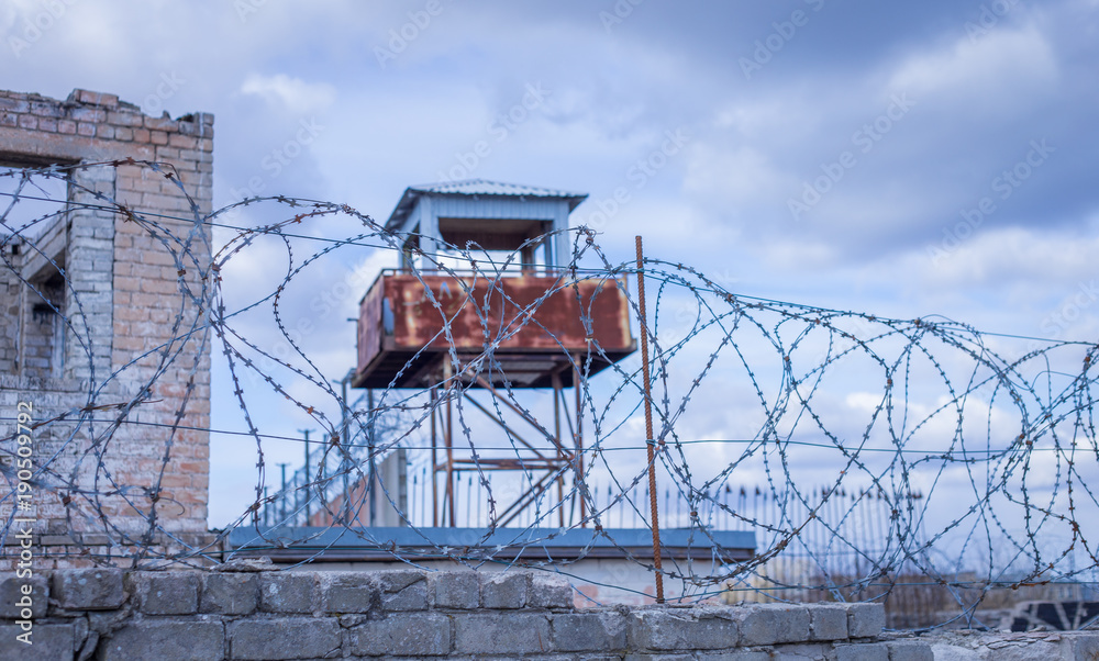 Historic brick prison wall showing guard tower and coiled barbed wire ...
